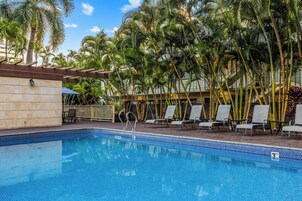 Piscina com espreguiçadeiras e palmeiras.