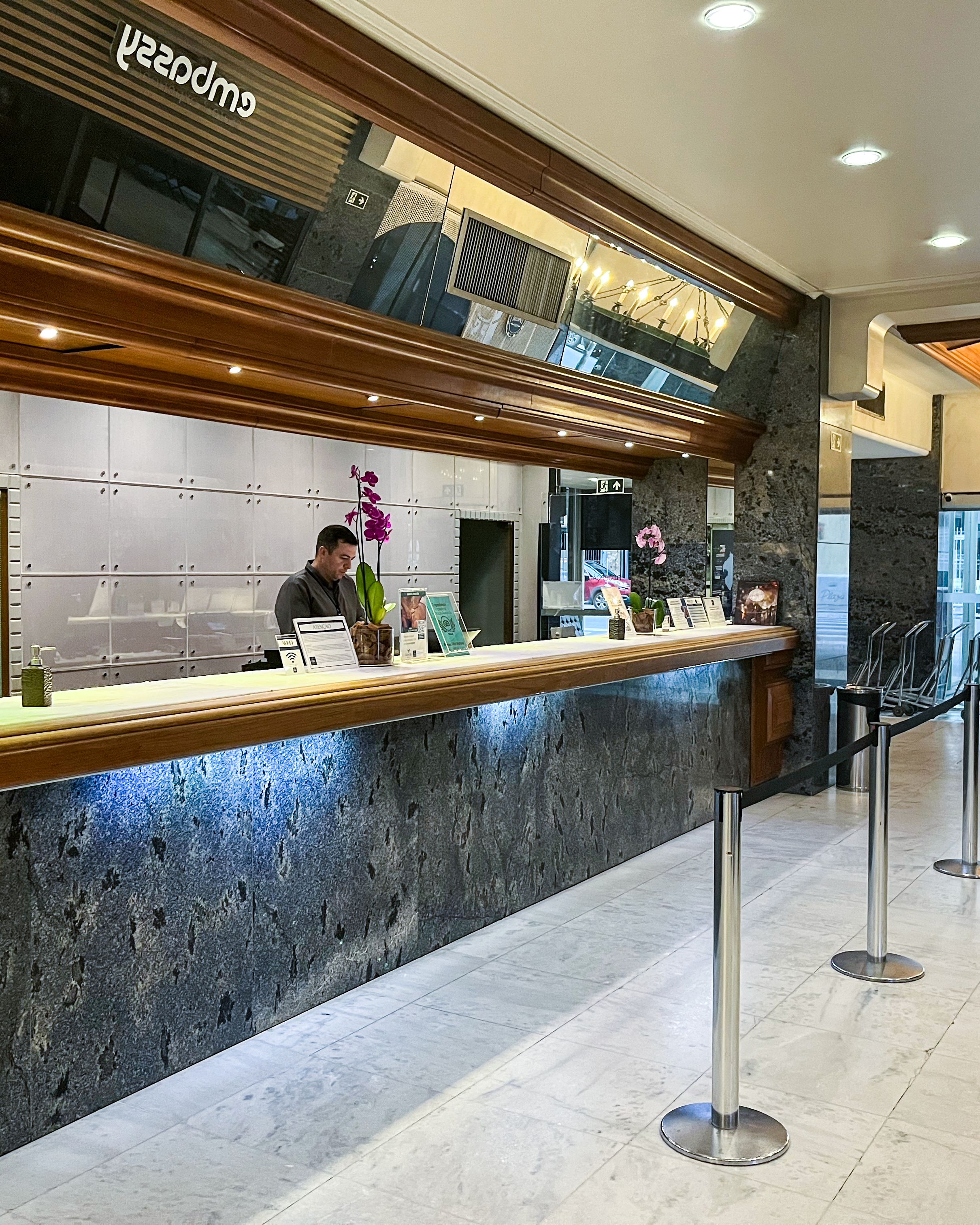 Bancada de recepção com design moderno, balcão e área de estar com estrutura metálica.