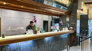 Bancada de recepção com design moderno, balcão e área de estar com estrutura metálica.