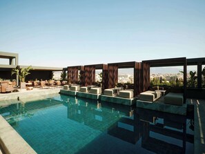 Área de piscina no terraço, com assentos e vista da cidade.
