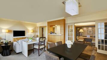 Quarto de hotel moderno com área de refeições, televisão de tela plana e espaço para sentar.