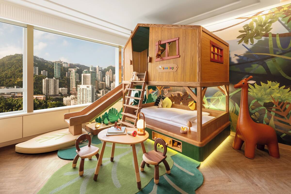 Um espaço de brincadeiras infantis com uma casinha de madeira, vista para a cidade e uma decoração de girafa.