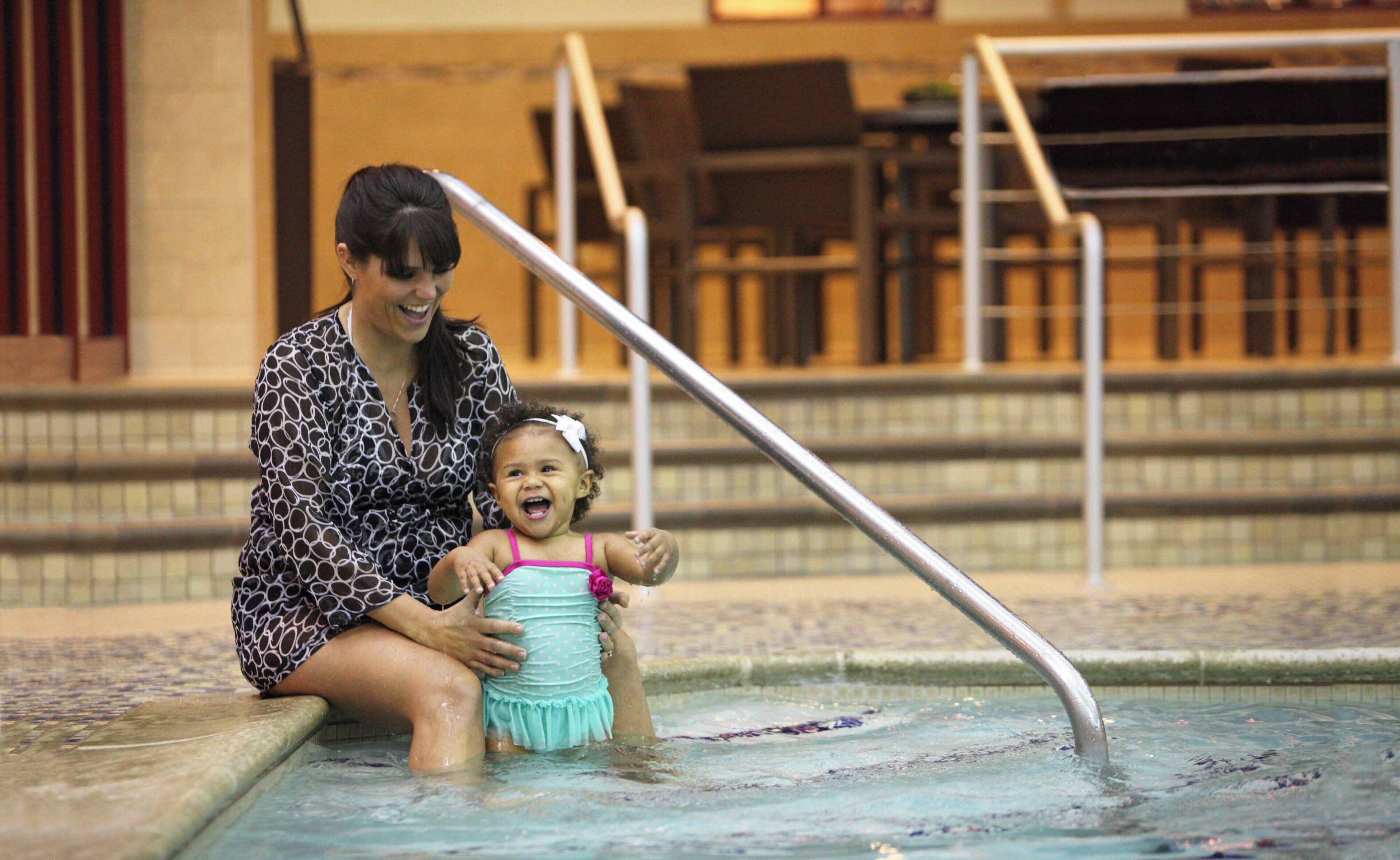 Uma mulher e uma criança perto de uma piscina com grade de metal.