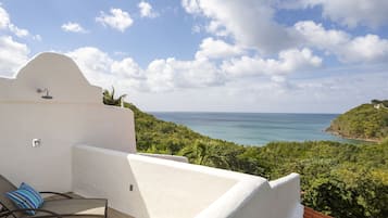Uma varanda com vista para o oceano e uma paisagem verdejante.