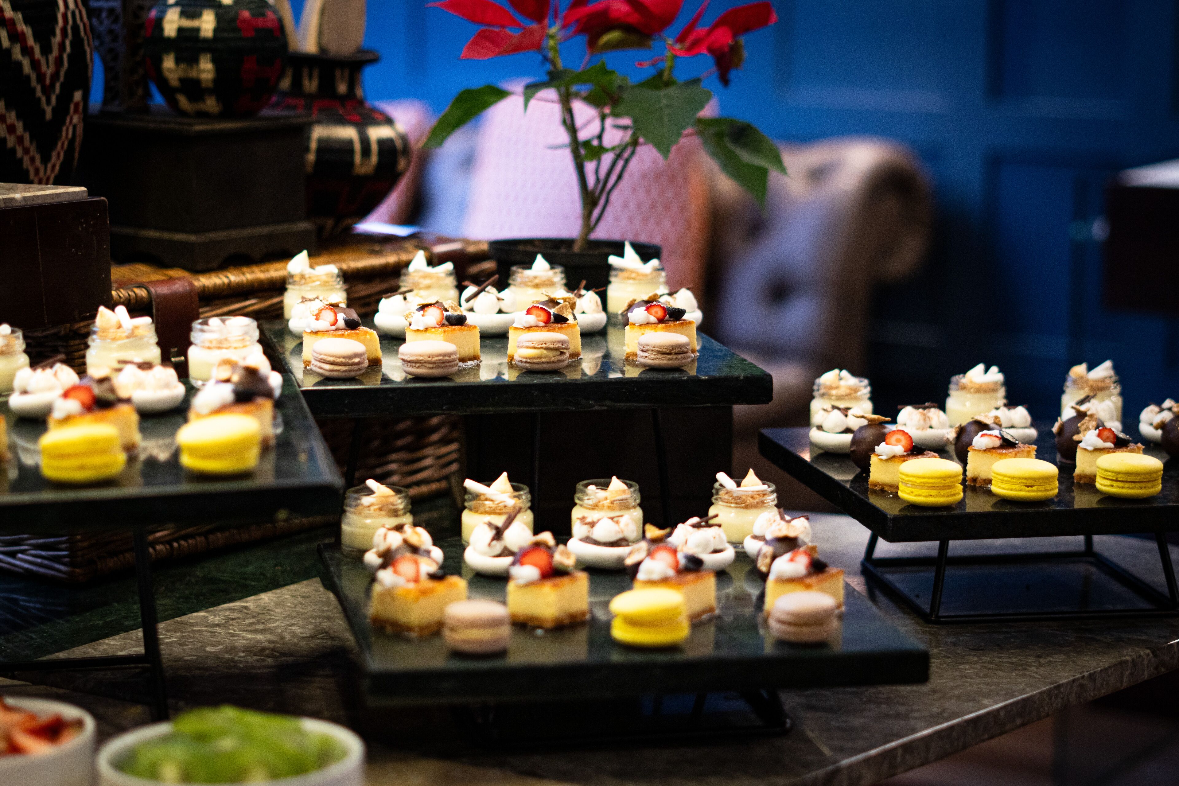 Diversos doces dispostos sobre uma mesa, incluindo macarons e pequenos bolos com coberturas.