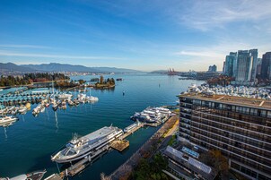 Marina com barcos atracados, um grande navio de cruzeiro e um edifício moderno com telhado plano.