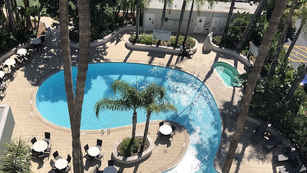 Área de piscina de resort com várias piscinas, espreguiçadeiras e mesas.