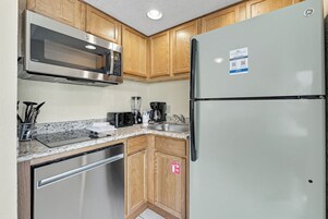 Cozinha compacta com geladeira de aço inoxidável, micro-ondas, torradeira e lava-louças.