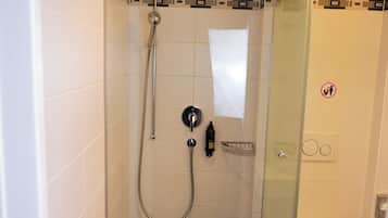 Um chuveiro moderno com box de vidro, chuveiro manual e torneira embutida na parede.
