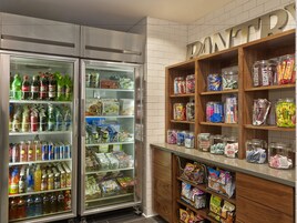 Um refrigerador cheio de bebidas diversas e uma prateleira com potes de lanches e doces.