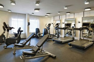 Uma academia com diversos equipamentos de exercícios, incluindo esteiras, bicicletas ergométricas e aparelhos de musculação.