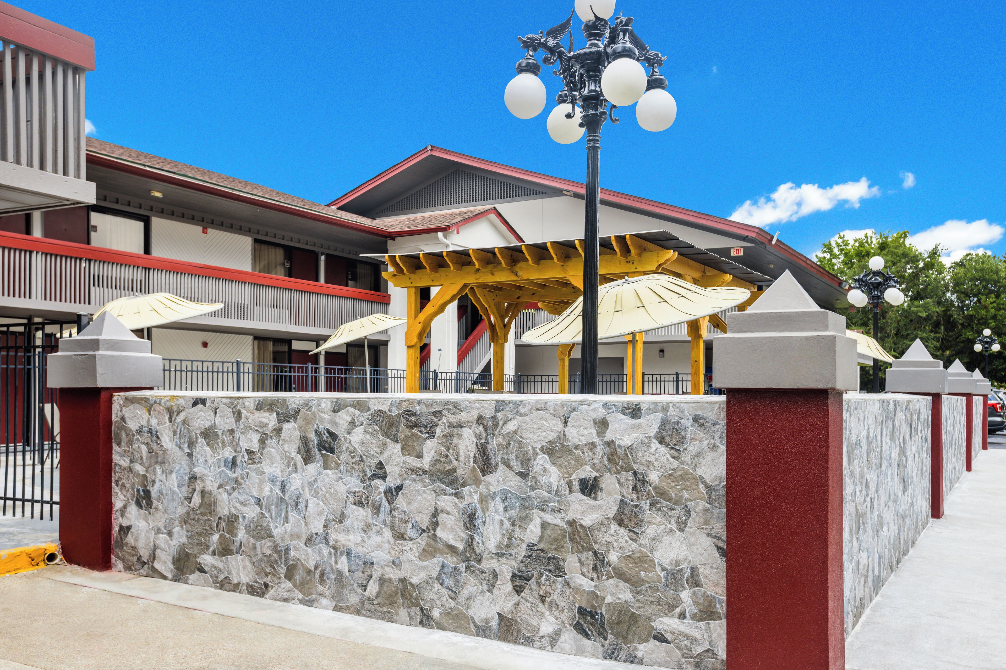 Um edifício com parede de pedra, área externa coberta com guarda-sóis e um poste de iluminação.