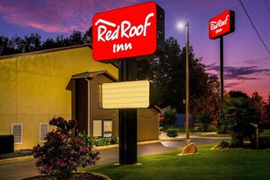 Um Red Roof Inn com uma grande placa, fachada do prédio e estacionamento.
