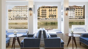 Uma sala de estar moderna com vista para um horizonte urbano através de grandes janelas.