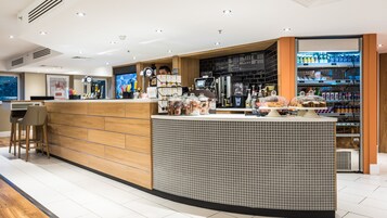 Uma área de bar moderna com balcão de madeira, painel de azulejos e espaço para sentar com banquetas.