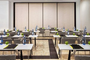 Uma sala de conferência com várias mesas, cadeiras e garrafas de água.