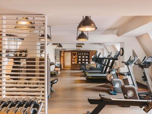 Uma academia com equipamentos de exercício, suportes para pesos e luminárias pendentes.