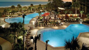 Um resort com várias piscinas, espreguiçadeiras e vista para o oceano.