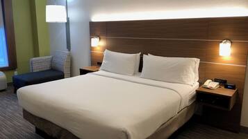 Quarto de hotel com uma cama grande, duas mesas de cabeceira, uma cadeira e uma luminária na parede.