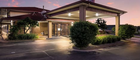Um hotel com entrada coberta, antena parabólica e acesso iluminado.