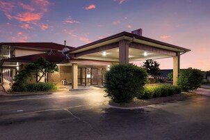 Um hotel com entrada coberta, antena parabólica e acesso iluminado.