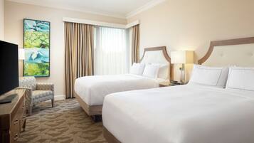 Quarto de hotel com duas camas, televisão, escrivaninha e uma cadeira.