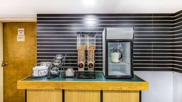 Um espaço de café com cafeteira, moedor e um recipiente de vidro com grãos de café.