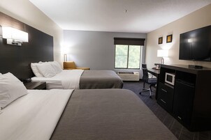 Quarto de hotel com duas camas, uma escrivaninha, televisão e janela.