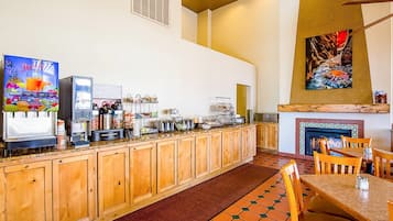Um balcão de café da manhã com geladeira, máquinas de café e um quadro na parede.