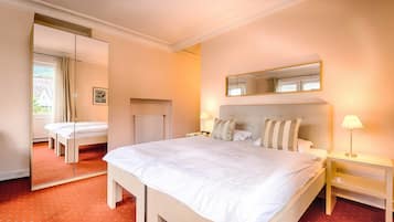 Quarto de hotel com uma cama grande, mesas de cabeceira, um espelho e vista para o exterior.