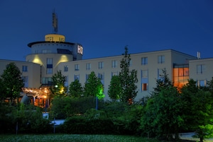 Um hotel com uma torre central identificada com a inscrição "HOTEL MESS" e um edifício moderno com várias janelas.