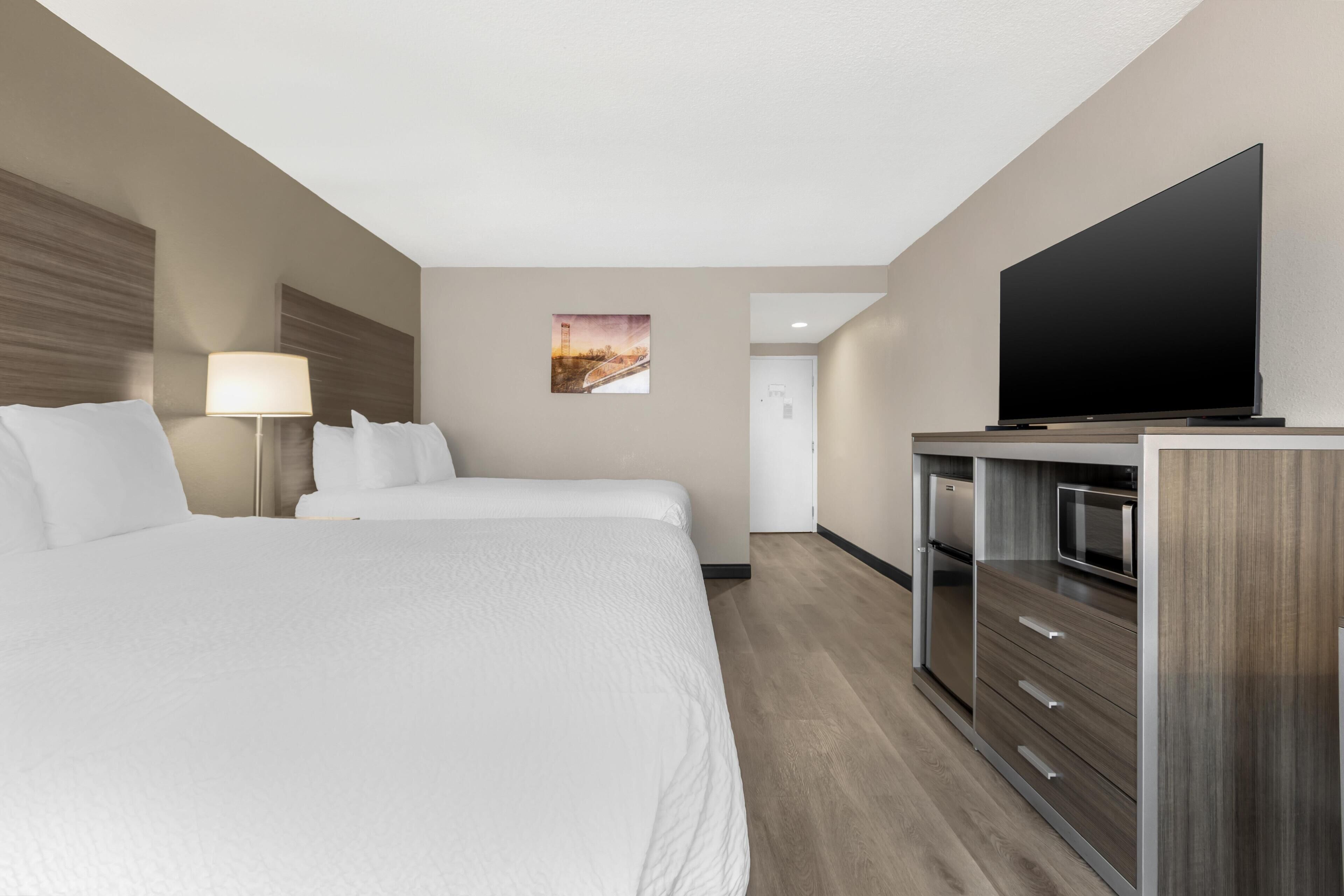 Quarto de hotel com duas camas, televisão de tela plana, micro-ondas e um pequeno armário.