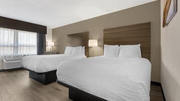 Quarto de hotel com duas camas, uma janela grande com cortinas, um abajur e um ar condicionado fixado na parede.