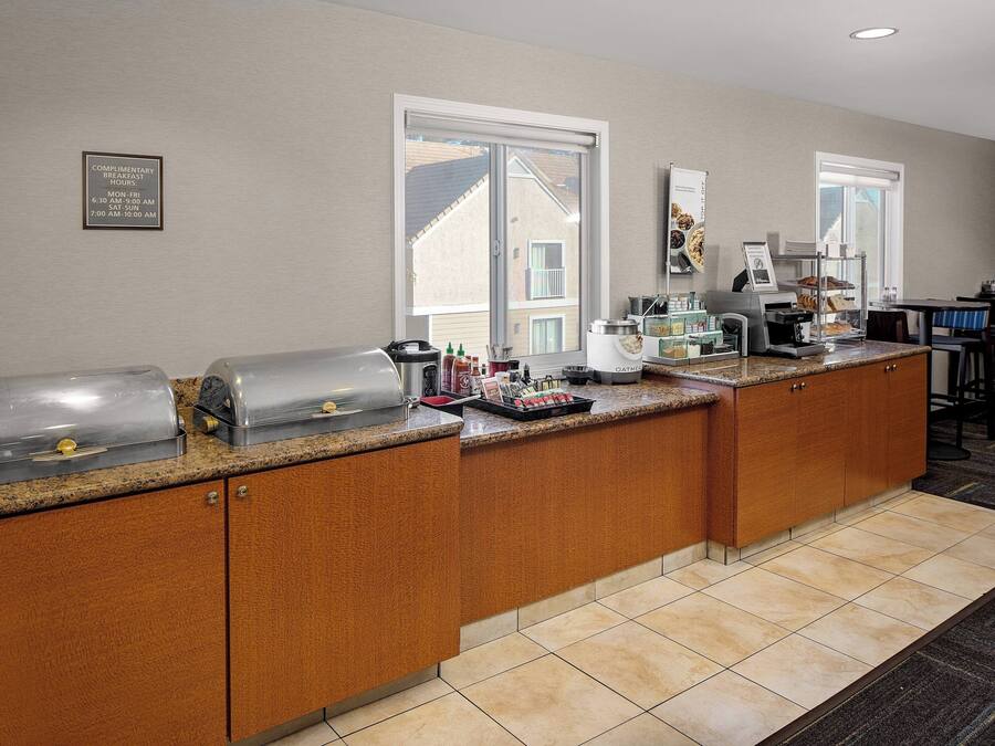 Uma área de cozinha com serviço de buffet, incluindo uma churrasqueira, máquina de café e diversos alimentos.