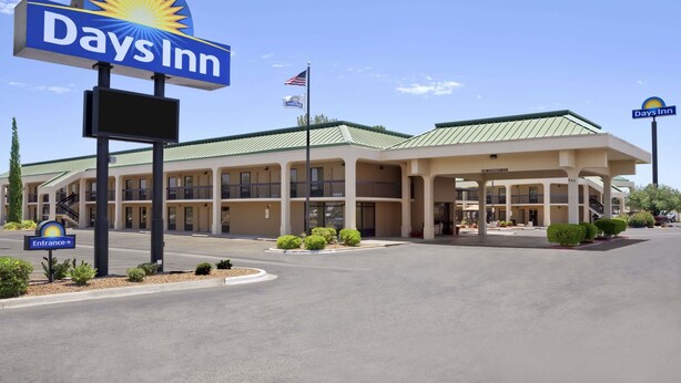 Um Days Inn com uma placa grande, uma bandeira e uma área de entrada bem cuidada.