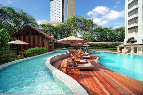 Piscina com deck de madeira, espreguiçadeiras e guarda-sóis.