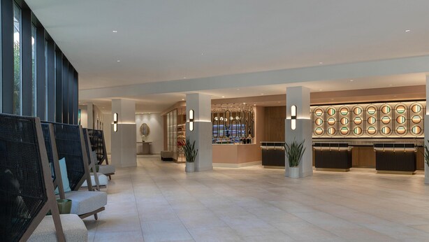 Um hall amplo com áreas de estar, balcão de recepção e uma parede com luminárias circulares.