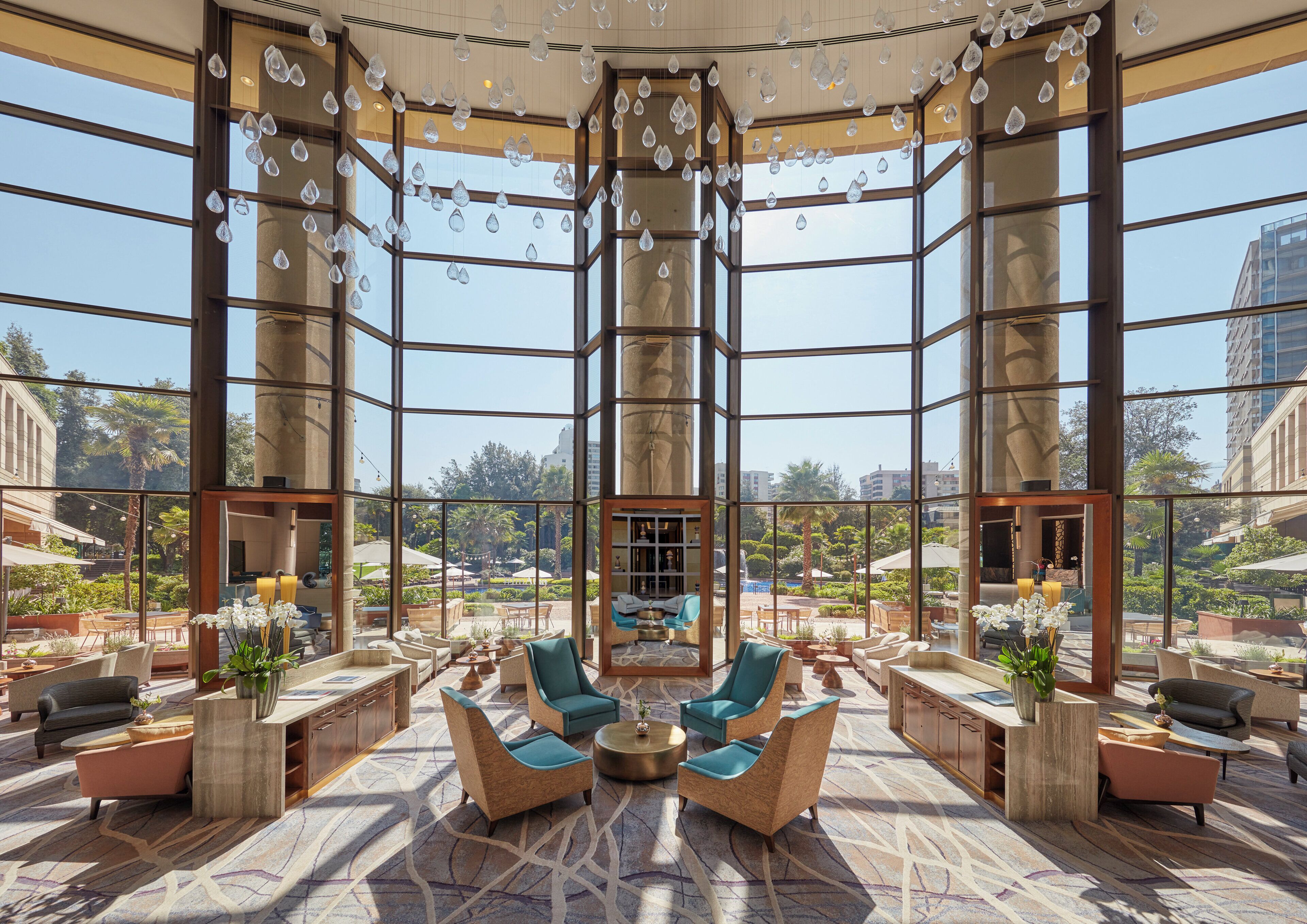Um hall amplo com design moderno, destacando uma grande área de estar, uma lareira central e vista para o jardim e área da piscina.
