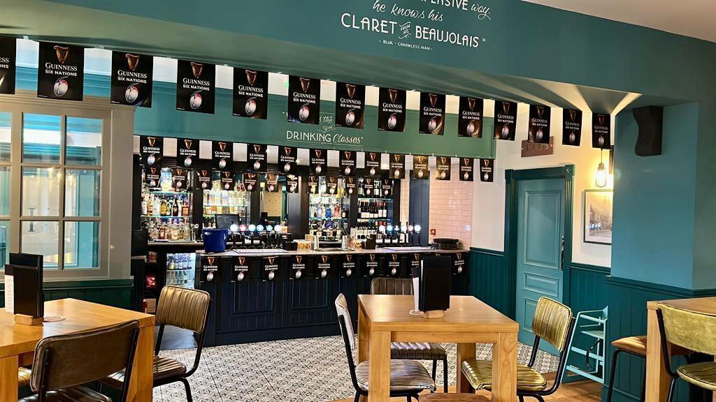 Uma área de bar com várias torneiras de cerveja Guinness e um letreiro com a inscrição 'AULAS DE DEGUSTAÇÃO'.