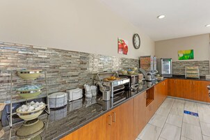 Cozinha moderna com painel de pedra, eletrodomésticos de aço inoxidável e um serviço de buffet.