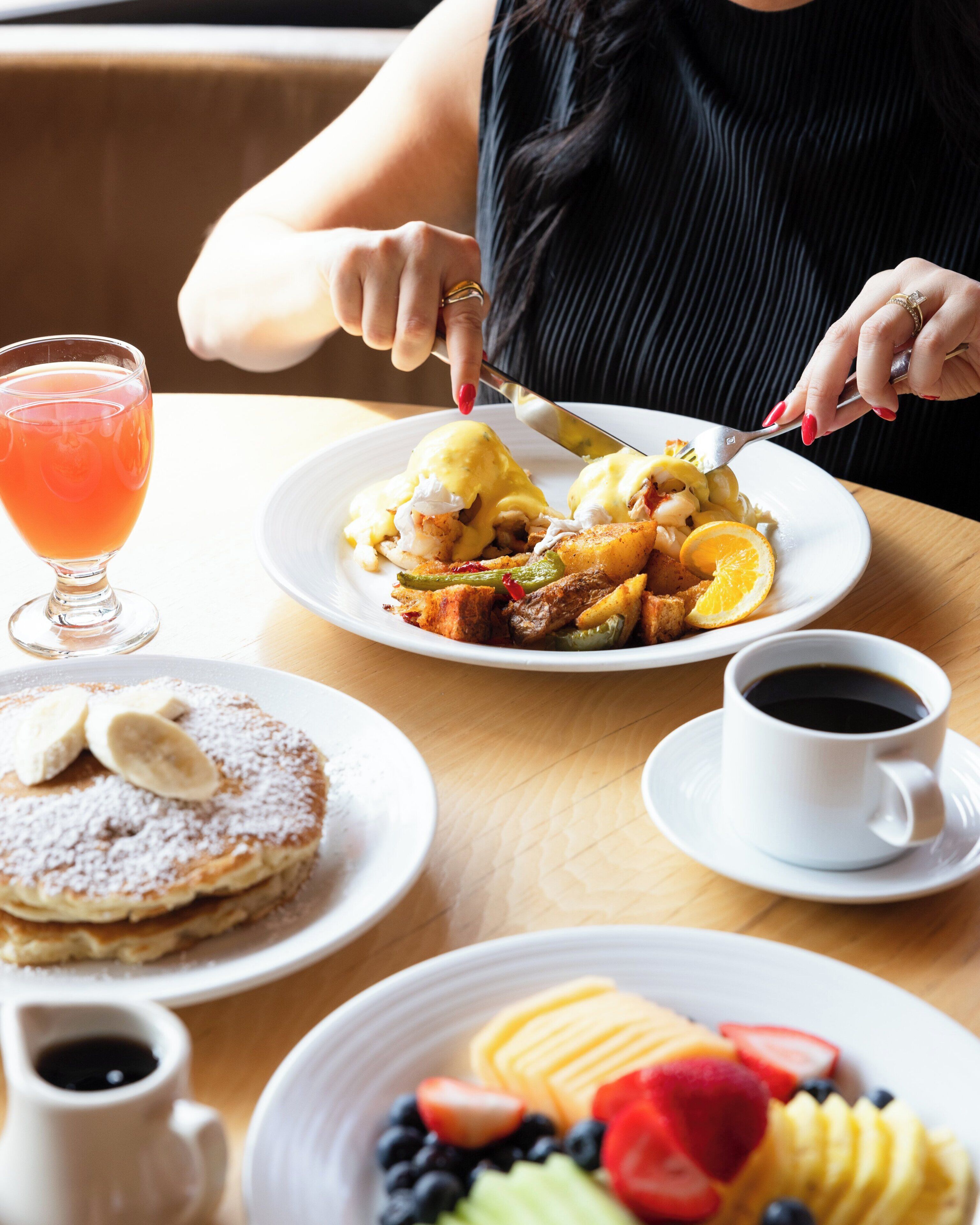 Uma mesa de jantar com pratos de café da manhã, um copo de suco de laranja e uma xícara de café.