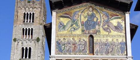 Um edifício histórico com uma torre alta e um mosaico detalhado na fachada.