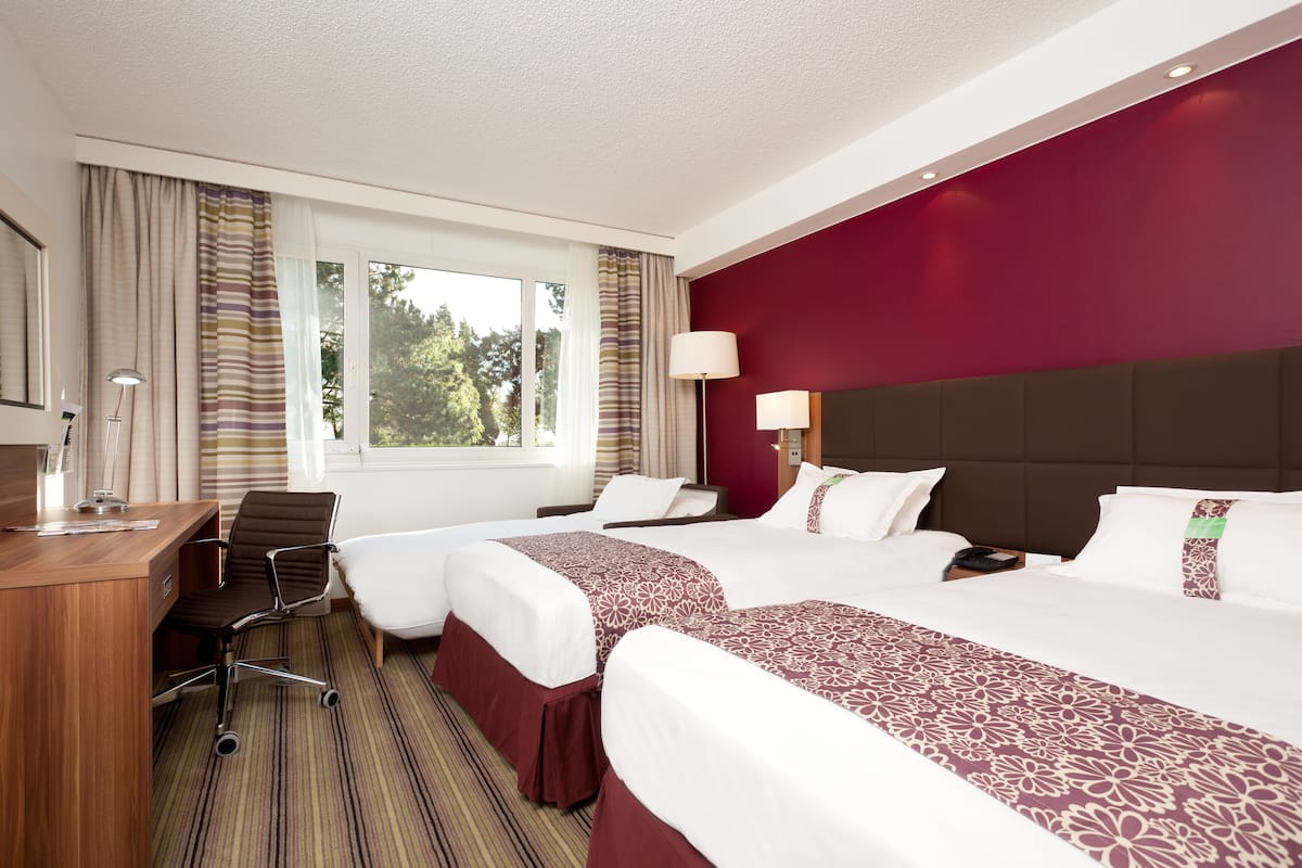Quarto de hotel com duas camas, uma escrivaninha e uma cadeira.