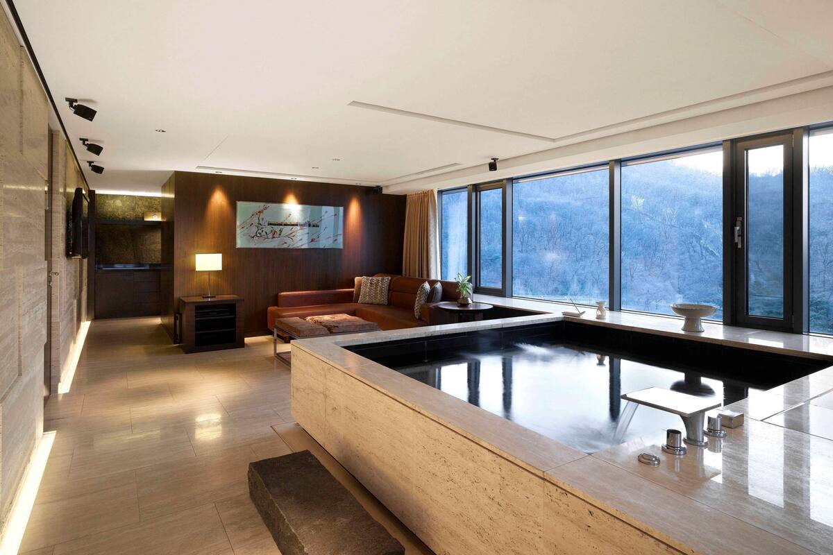 Um spa moderno com uma grande banheira de hidromassagem, um sofá e um quadro na parede.
