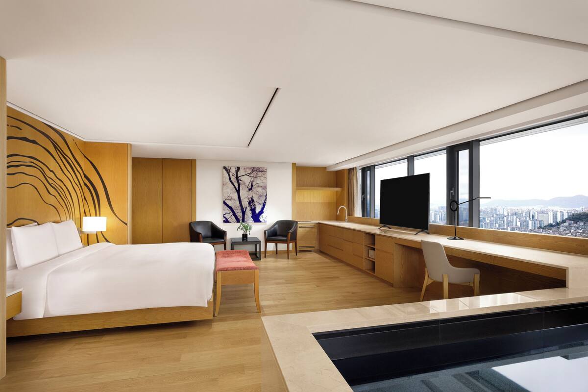 Quarto de hotel moderno com cama, escrivaninha e vista para a cidade.