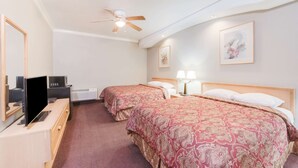 Quarto de hotel com duas camas, televisão, escrivaninha e ventoinha no teto.