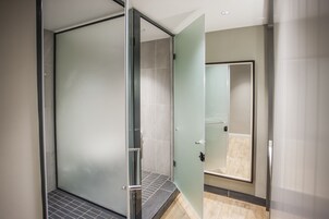 Um banheiro moderno com box de vidro, piso em azulejo e um espelho.