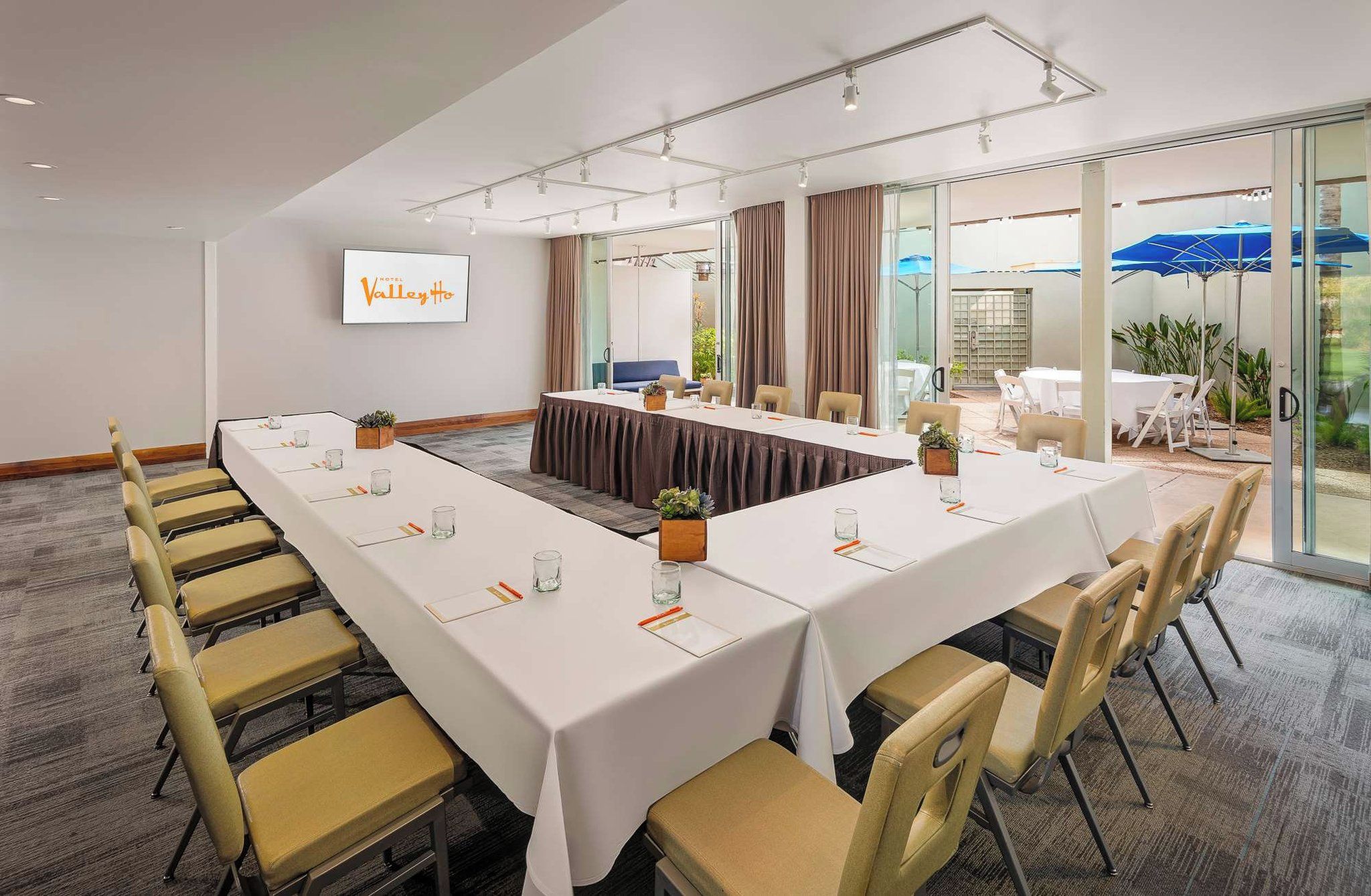 Uma sala de conferência com uma mesa comprida, cadeiras e uma placa indicando HOTEL Vallenotto.