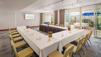 Uma sala de conferência com uma mesa comprida, cadeiras e uma placa indicando HOTEL Vallenotto.