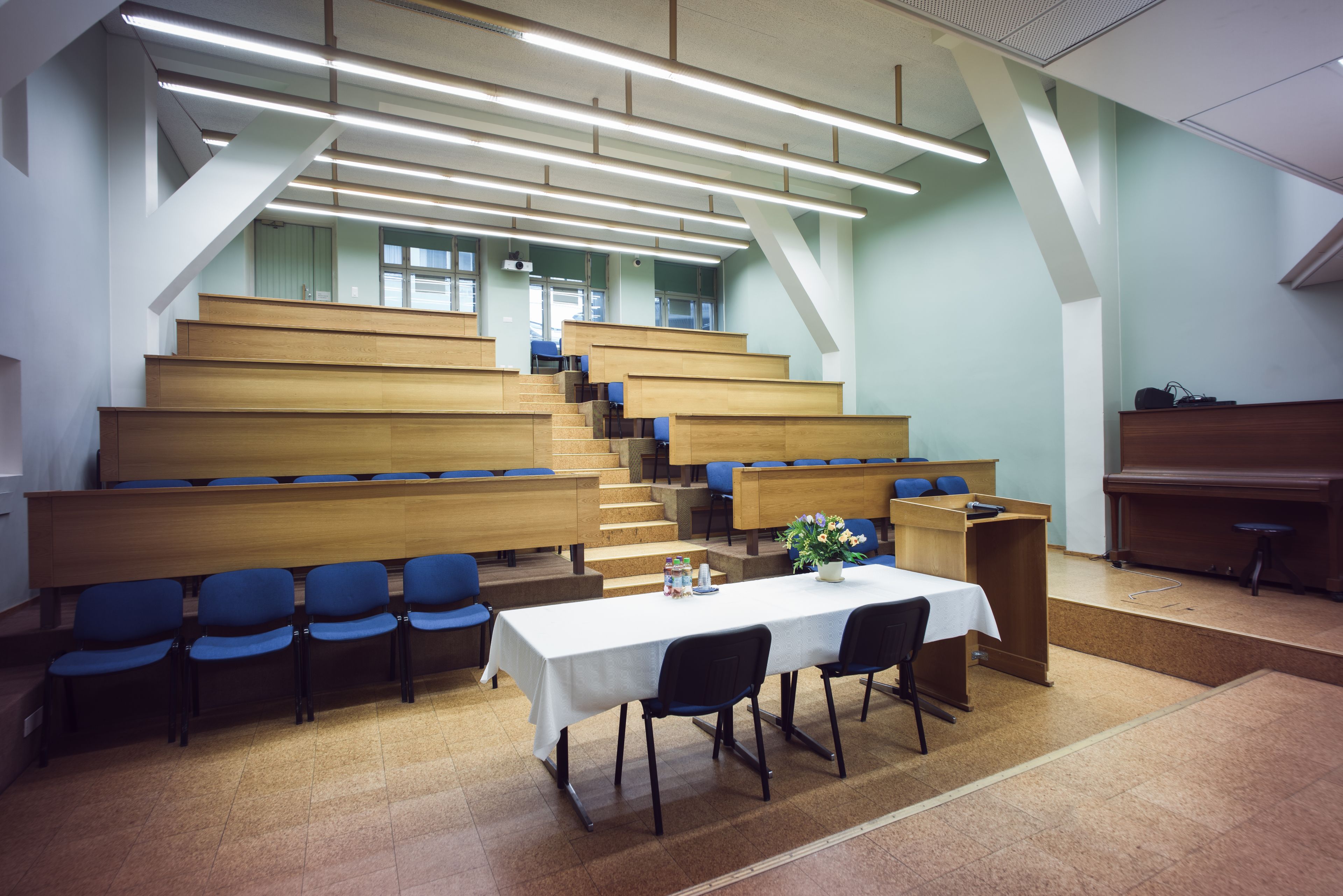 Auditório com assentos em níveis, um púlpito e uma mesa com cadeiras.